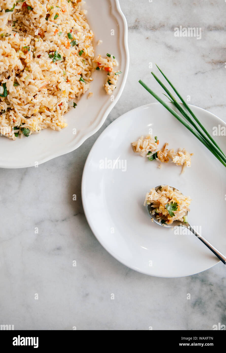 Thai fried rice in white dish and in spoon on side plate with marble ...