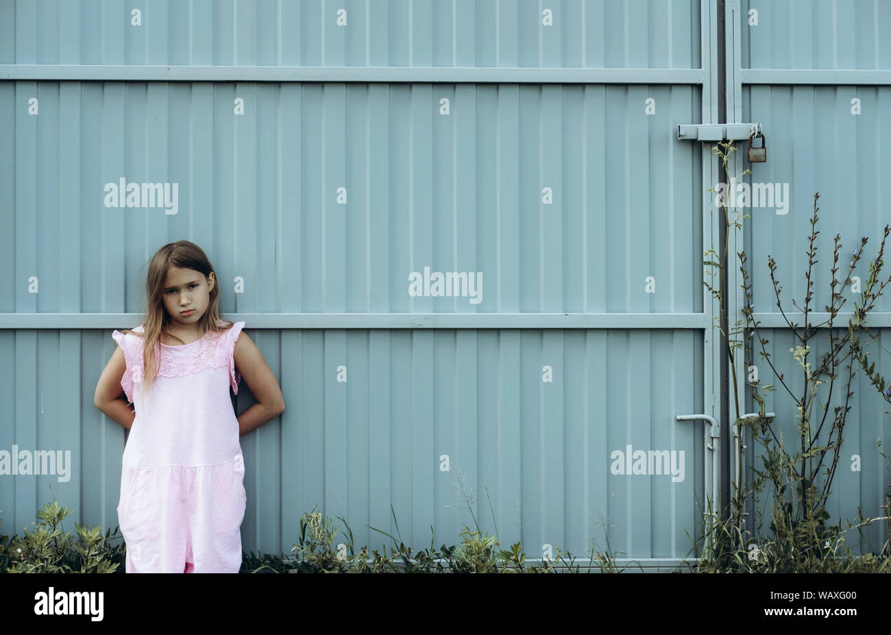Little serious girl posing near metal gates outdoor. Young beautiful ...