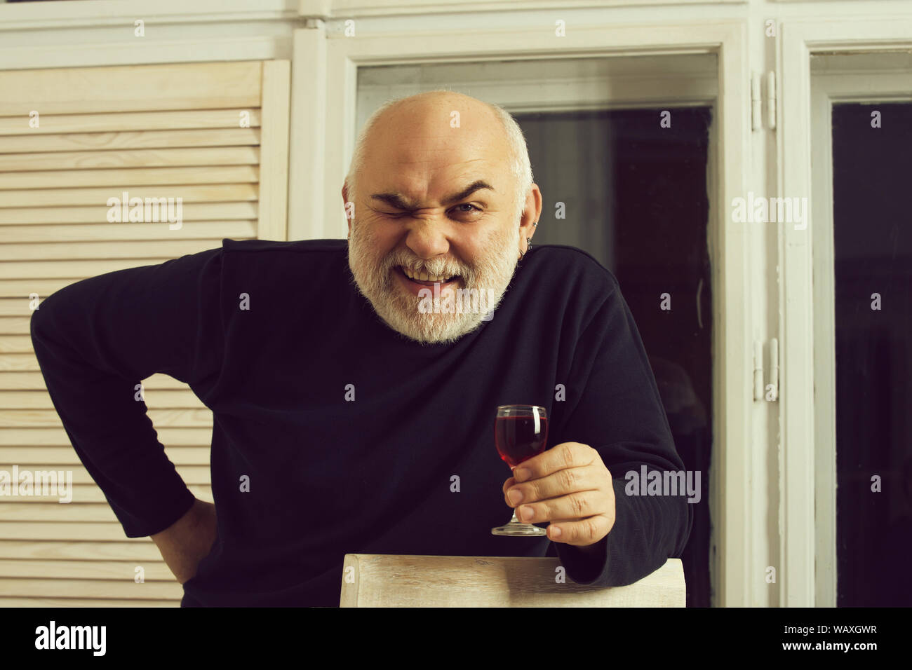 Man winking with glass of wine. Happy pensioner or senior person with ...