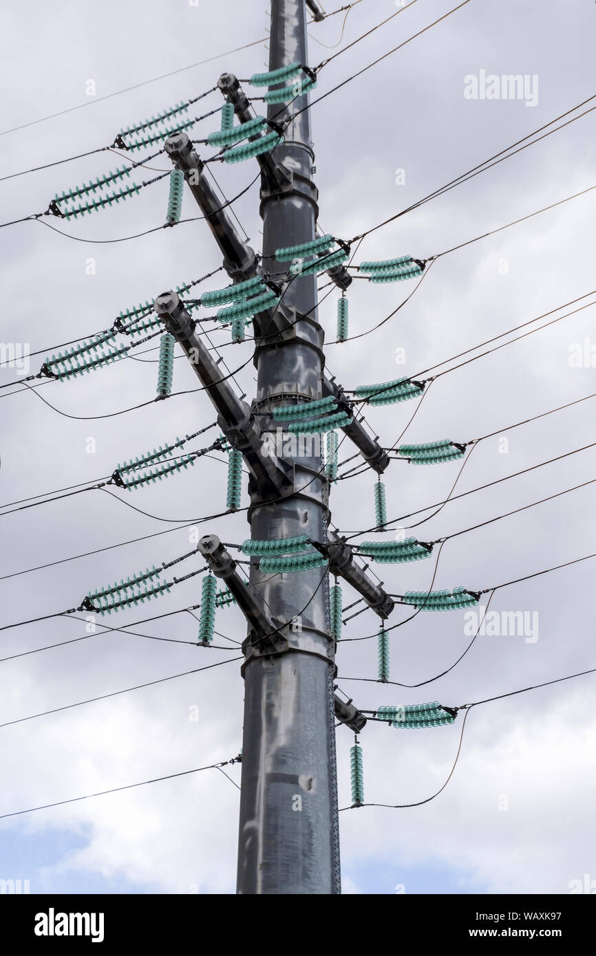 fragment of a massive power line pylon with green insulators and wires ...