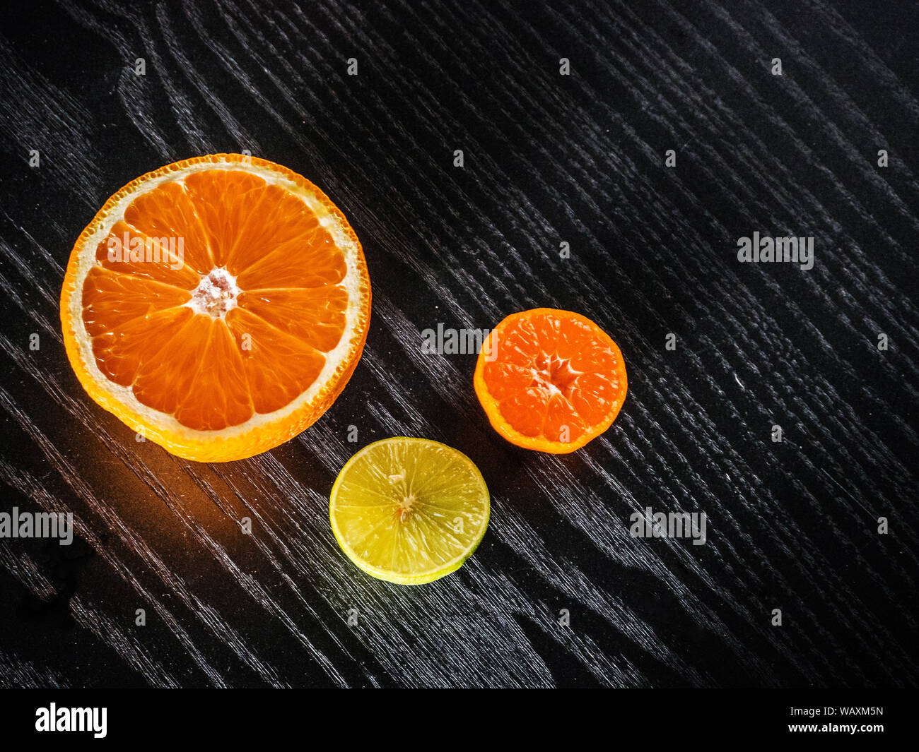 fresh halves oranges and lime with copy space on black table background ...