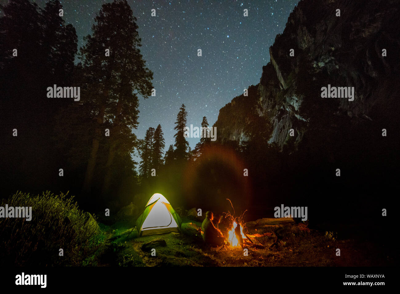 campfire under night sky with star on top of mountain surrounded by ...