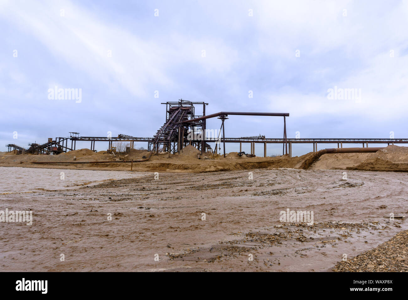 rusty pipe on the river bank, from which sewage flows, dirty sand ...
