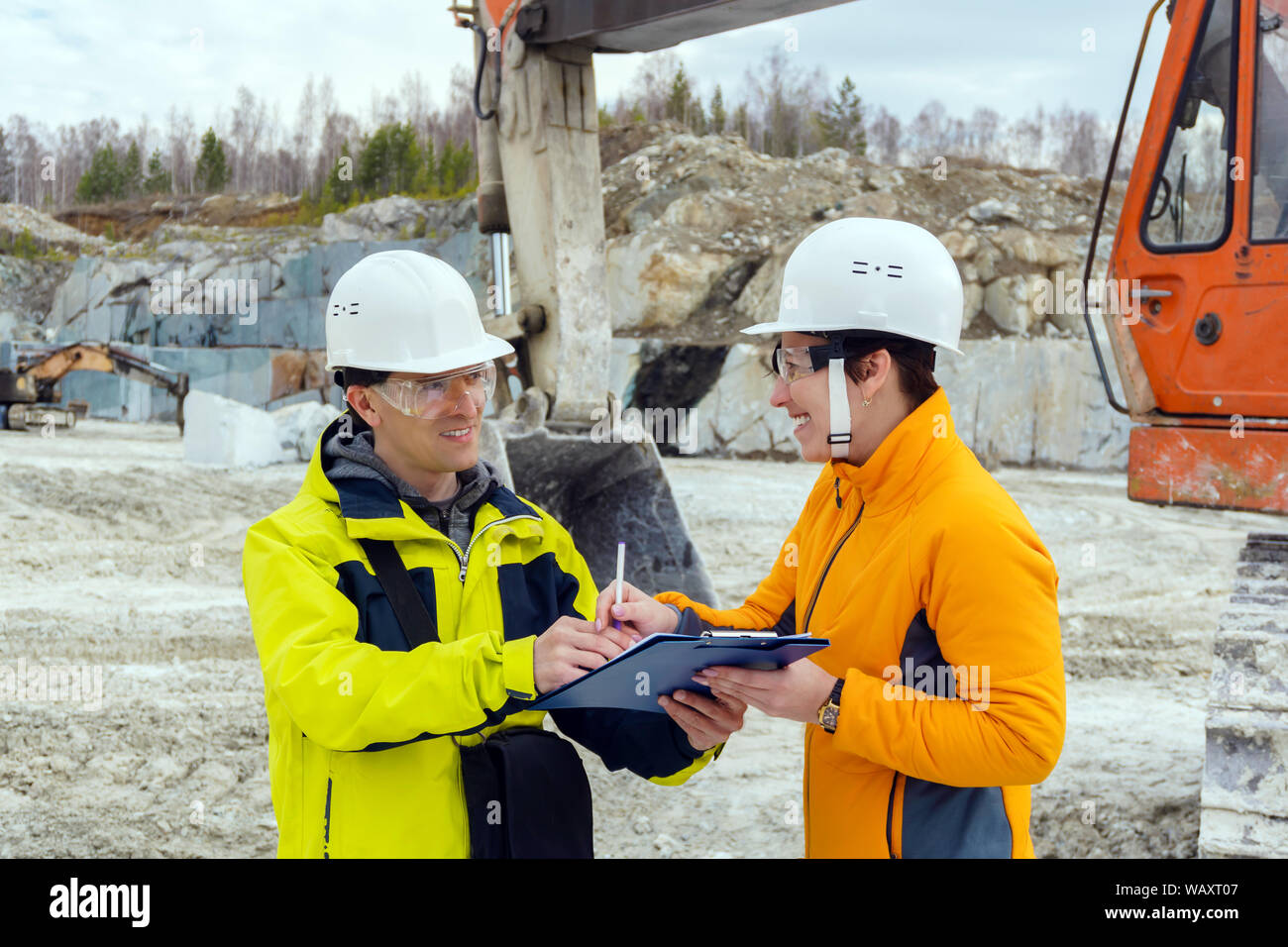 a man and a woman workers in helmets sign a document against the ...