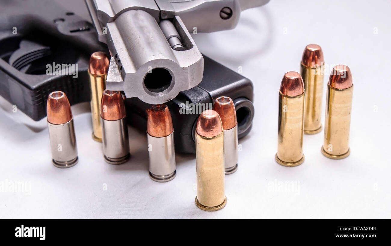 A snub nosed, stainless 357 magnum revolver on top of a black 9mm ...