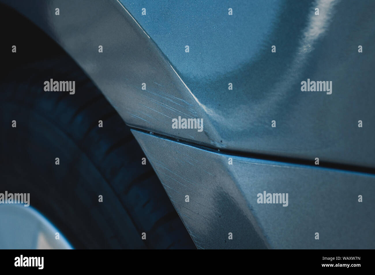 Scuffing on the wing and bumper of the car. Summer, gray car. Close-up ...