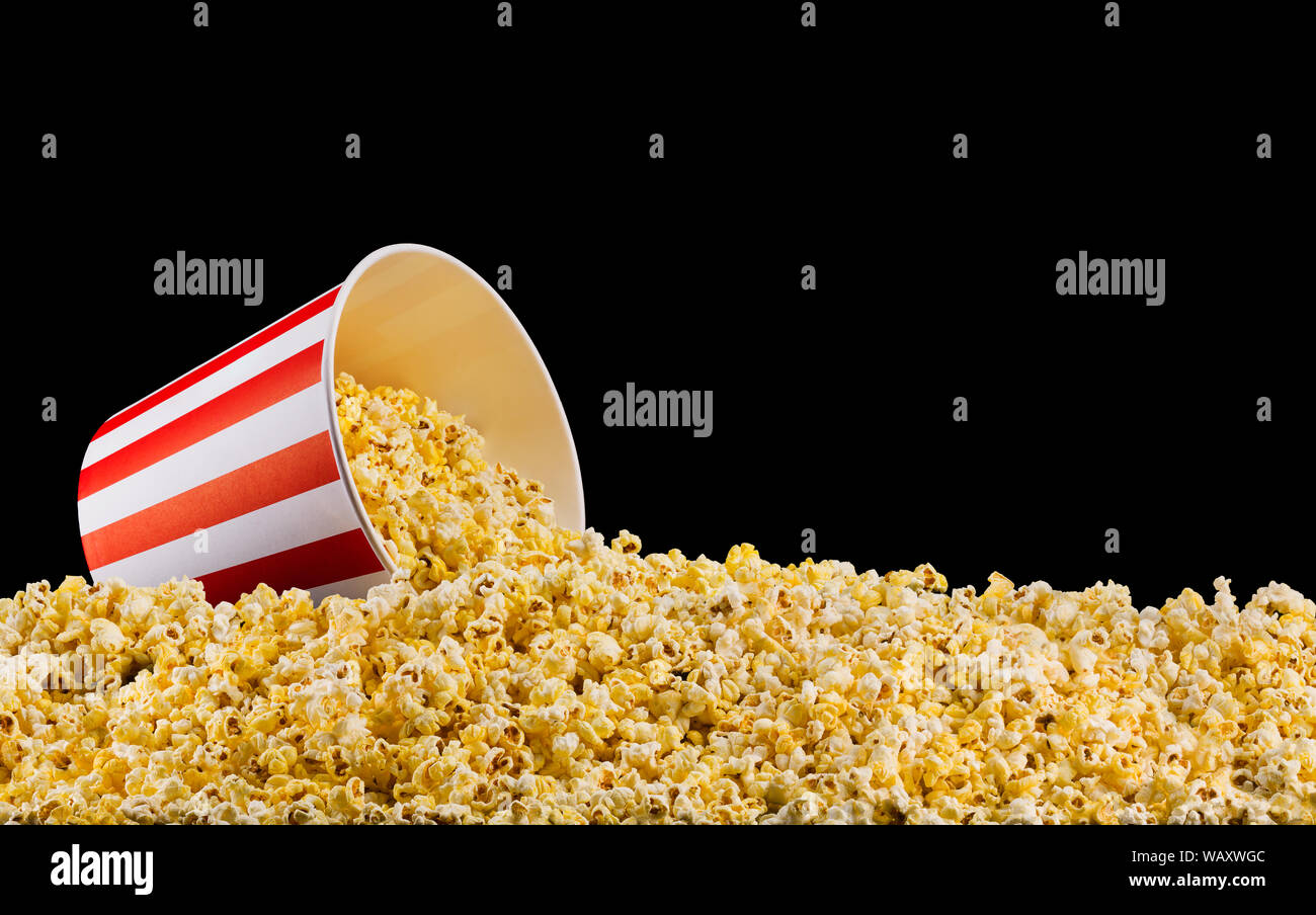 Scattered popcorn from paper striped bucket isolated on black ...