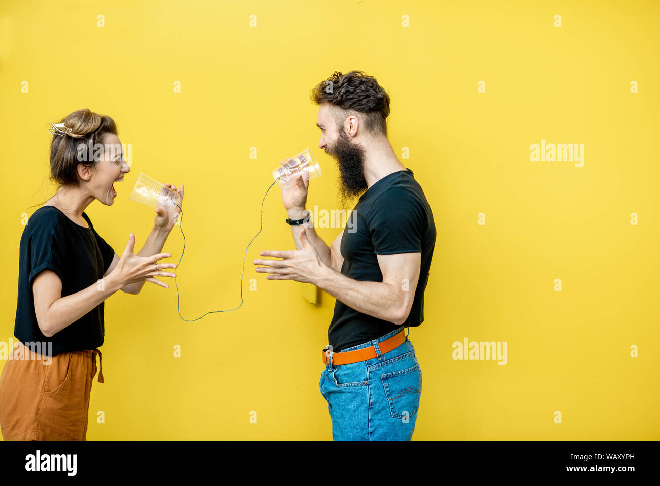 Man and woman talking with string phone, shouting on each other on the ...