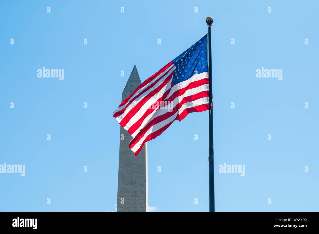 US flag flying from a pole with Washington Monument in background Stock ...
