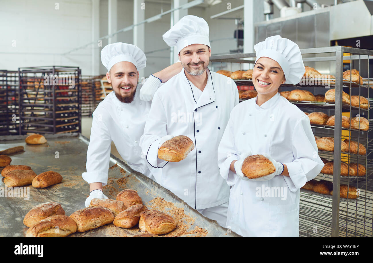 Bakers smiling holding fresh bread in their hands in a bakery Stock ...