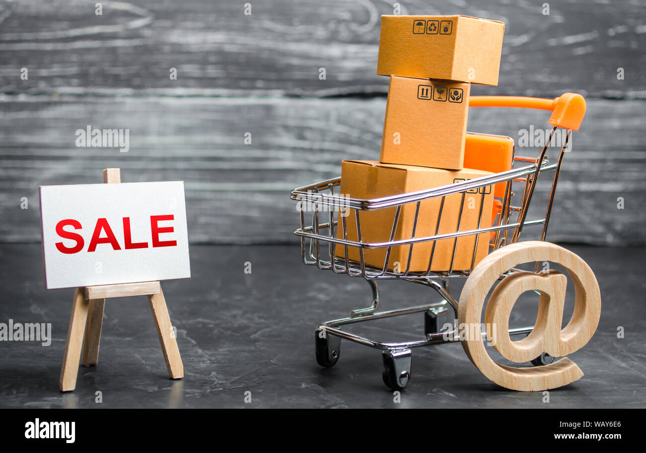 A shopping cart filled with cardboard boxes and an easel with the word ...