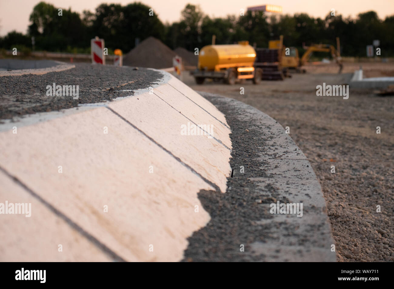 Road construction site, focus on curbs with a tanker truck in the ...