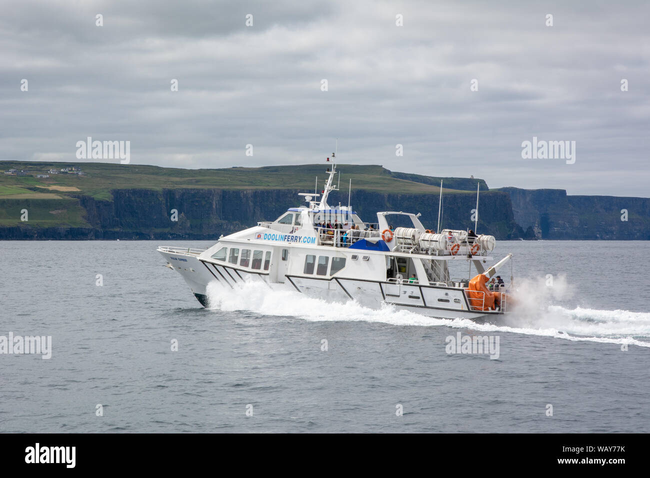 Ferry boat cruises past Cliffs of Moher during summer sailing between ...
