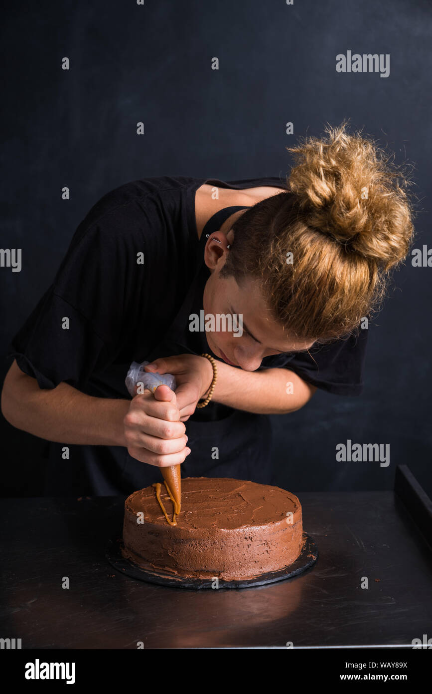 Men in black decorating chocolate cake with caramel Stock Photo - Alamy