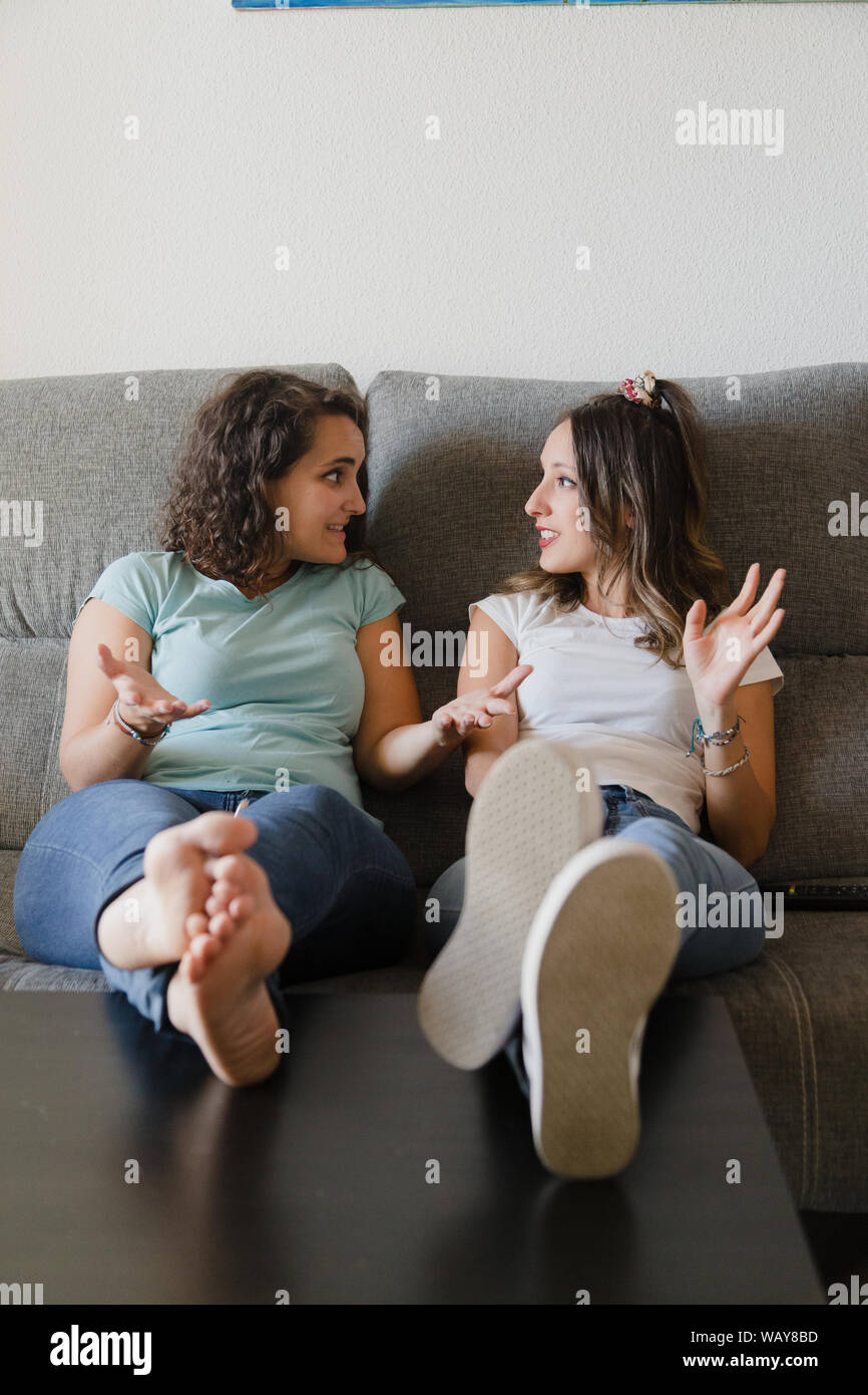 Girls in a couch with feet in a table talking Stock Photo - Alamy