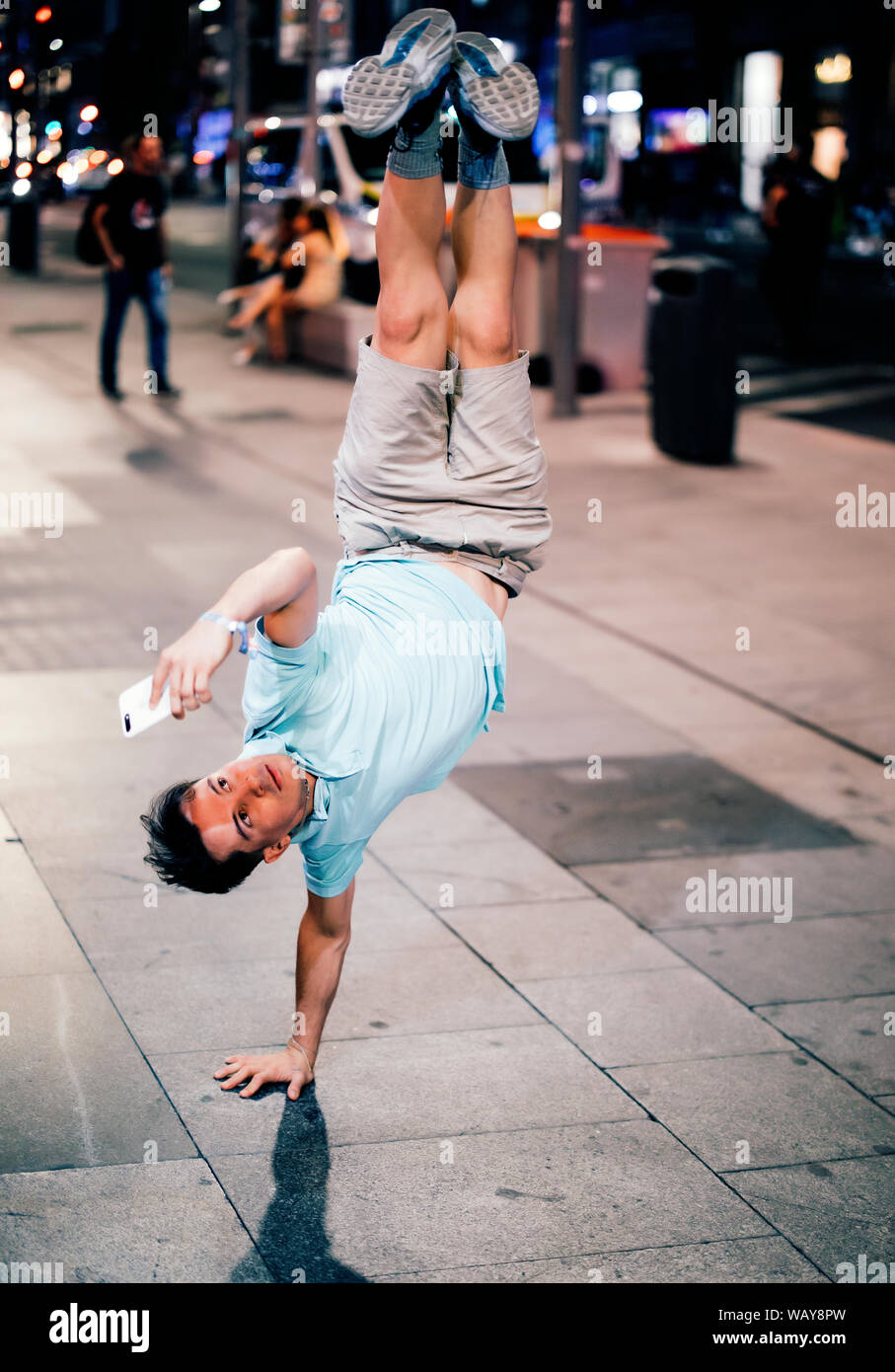 A young man dancing break dance on the night city road and consulting ...