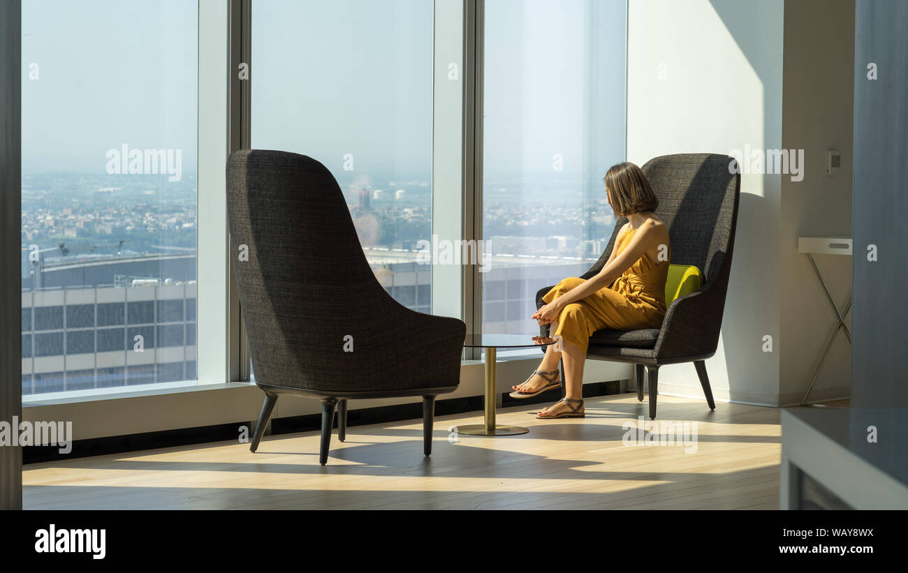 Woman in yellow suit looking outside of the giant window in New York ...