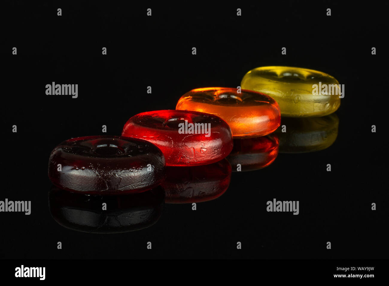 Group of four whole colourful hard candy dark red cherry orange and ...