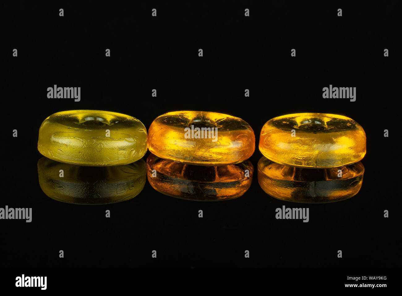 Group of three whole yellow colourful hard candy isolated on black ...