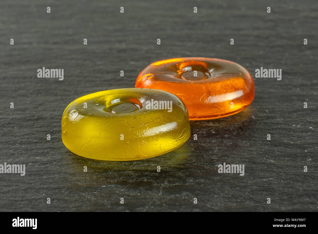 Group of two whole yellow orange colourful hard candy on grey stone ...