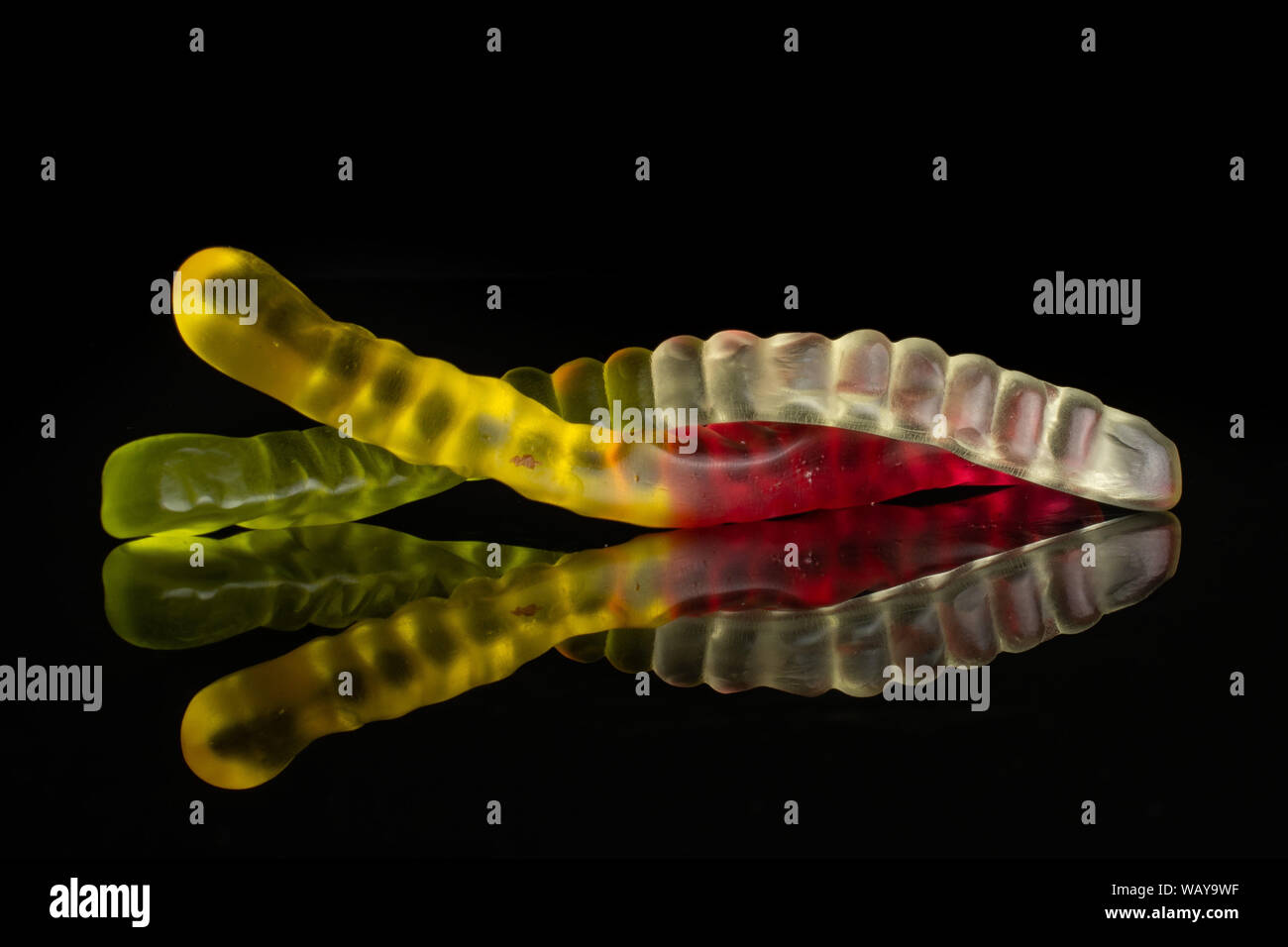 Group of two whole colourful jelly worm candy isolated on black glass ...