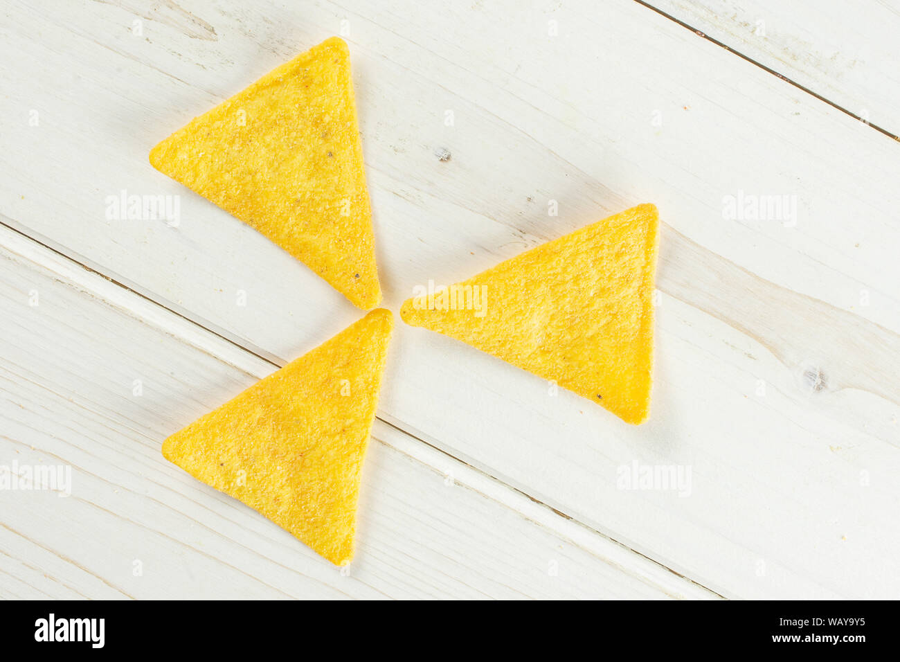 Group of three whole cheese tortilla chips like hazard symbol flatlay ...