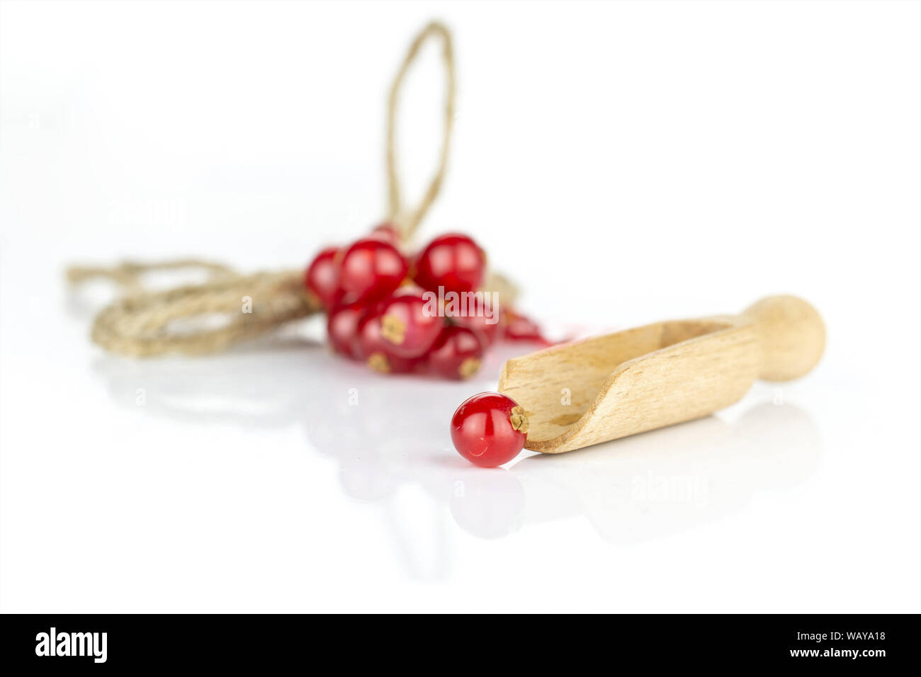 Lot of whole fresh red currant with wooden scoop and jute rope isolated ...