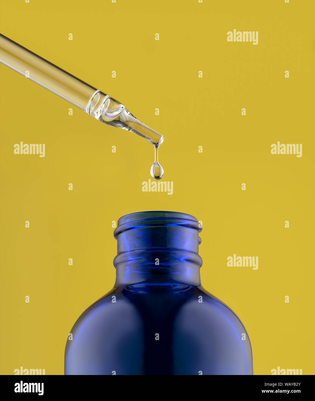 Essential Oils Bottle with Dropper and a Hanging Drop on Yellow ...