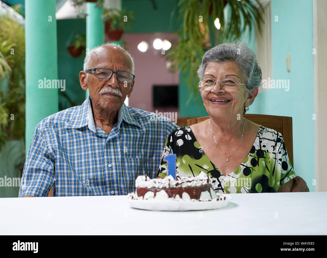 Elder couple with a cake on a table and the number 1 on the cake Stock ...
