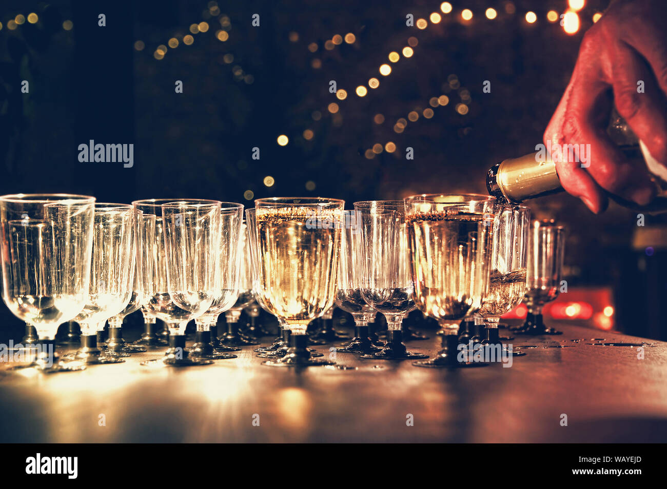 Man pouring wine in the glass on holiday table in night-time lighting ...