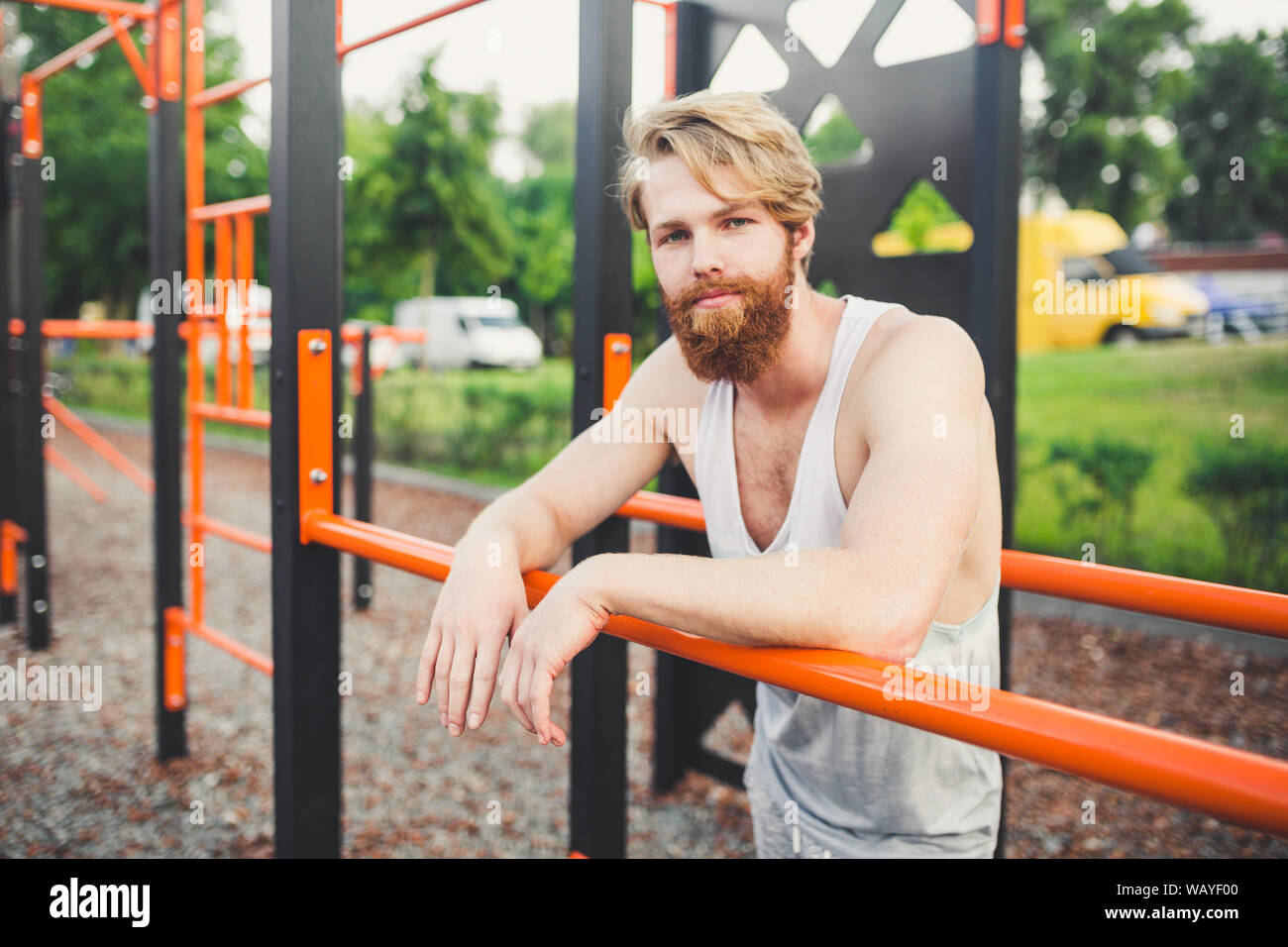 Portrait young bearded man standing on public sports ground and ...