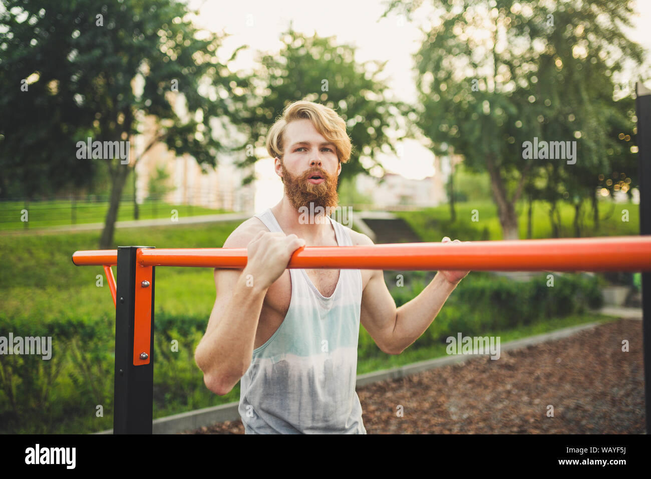 Portrait of Tired Athlete at Gym. Tired man hanging from the bar ...