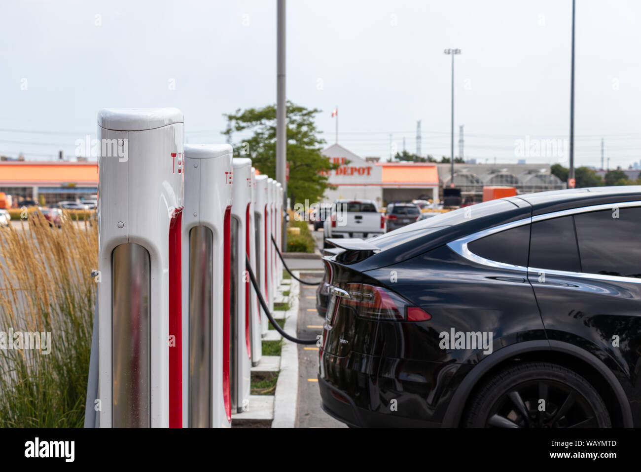 Black Tesla Model X plugged-in at Tesla Supercharger on a bright summer ...