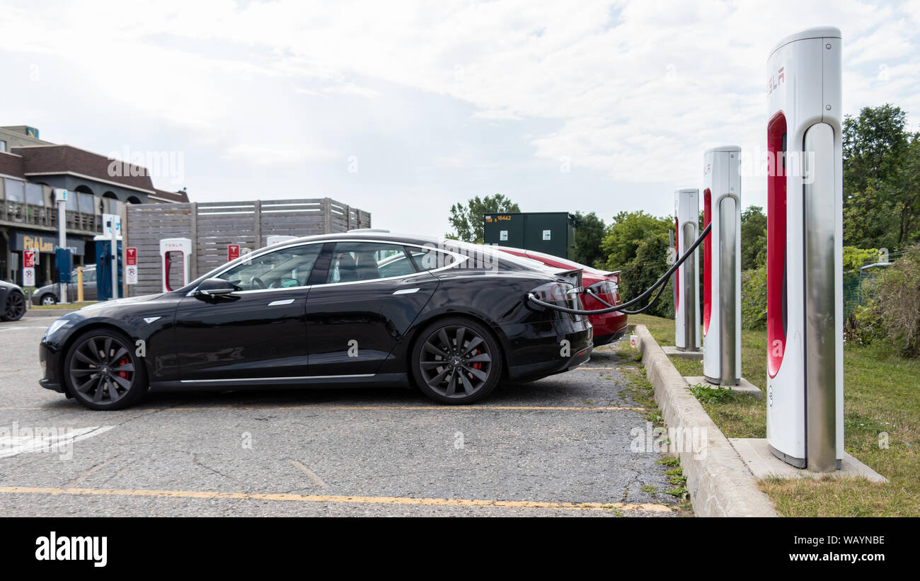 Black Tesla Model S plugged-in and charging at Tesla Supercharger ...