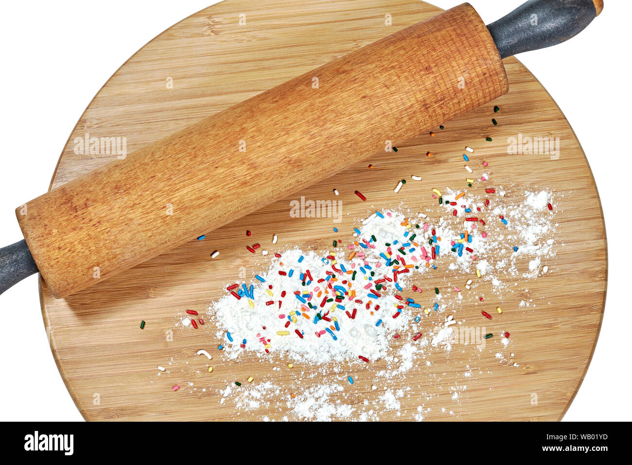 A wooden rolling pin on a bamboo cutting board with white flour and ...
