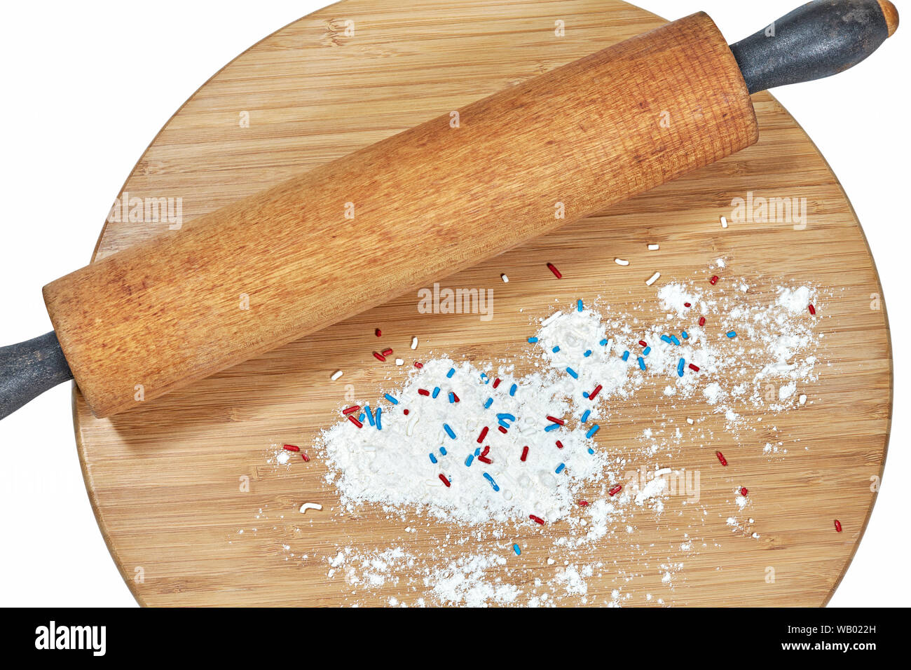 A wooden rolling pin on a bamboo cutting board with white flour and red ...