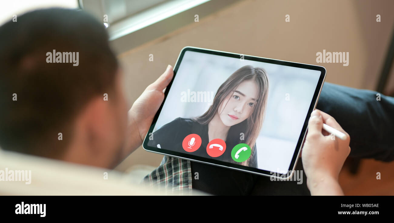 Young businessman making video calls with his friend on tablet while ...