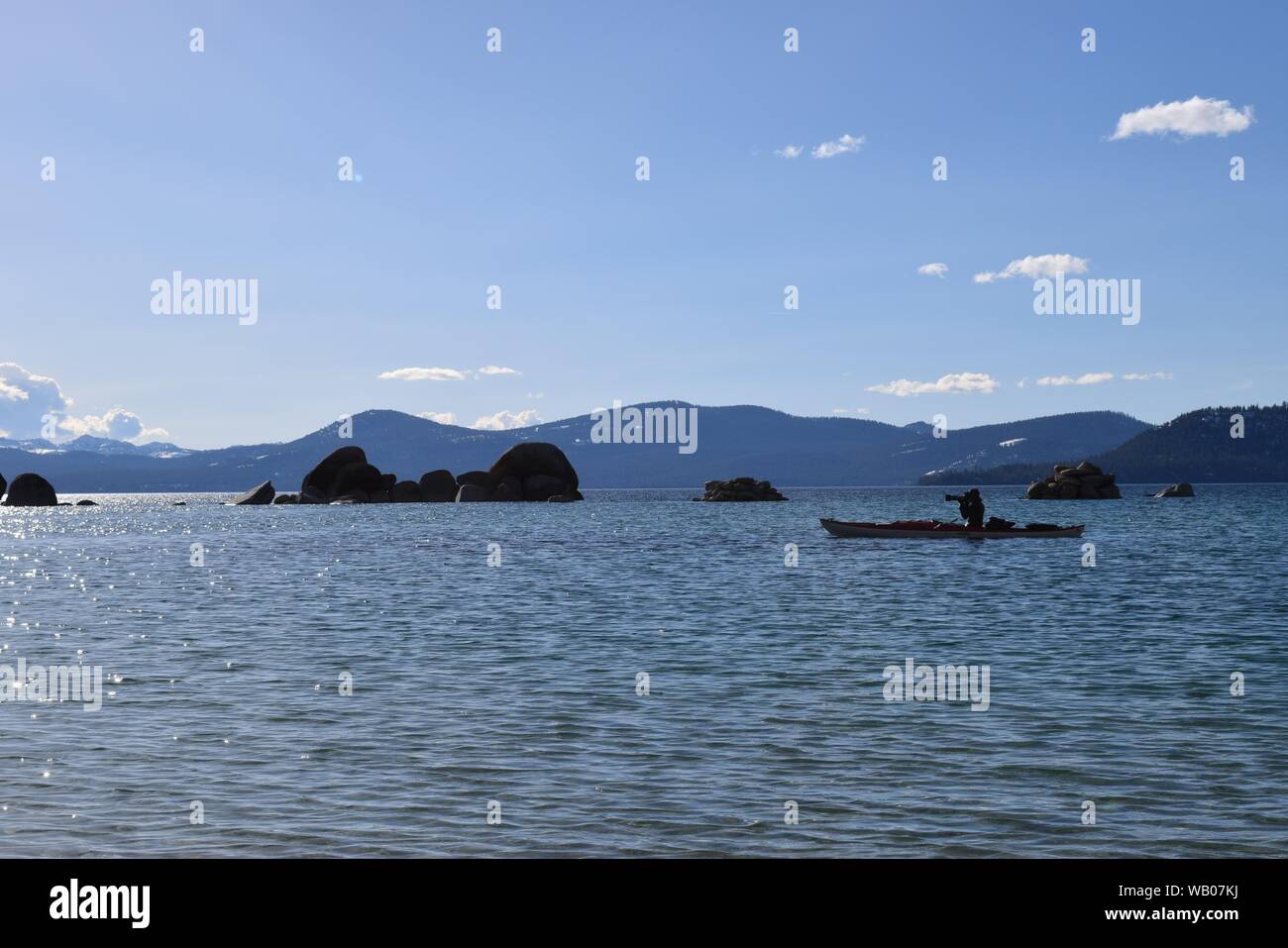 a canoe on the body of water with rock formations under a blue sky at ...