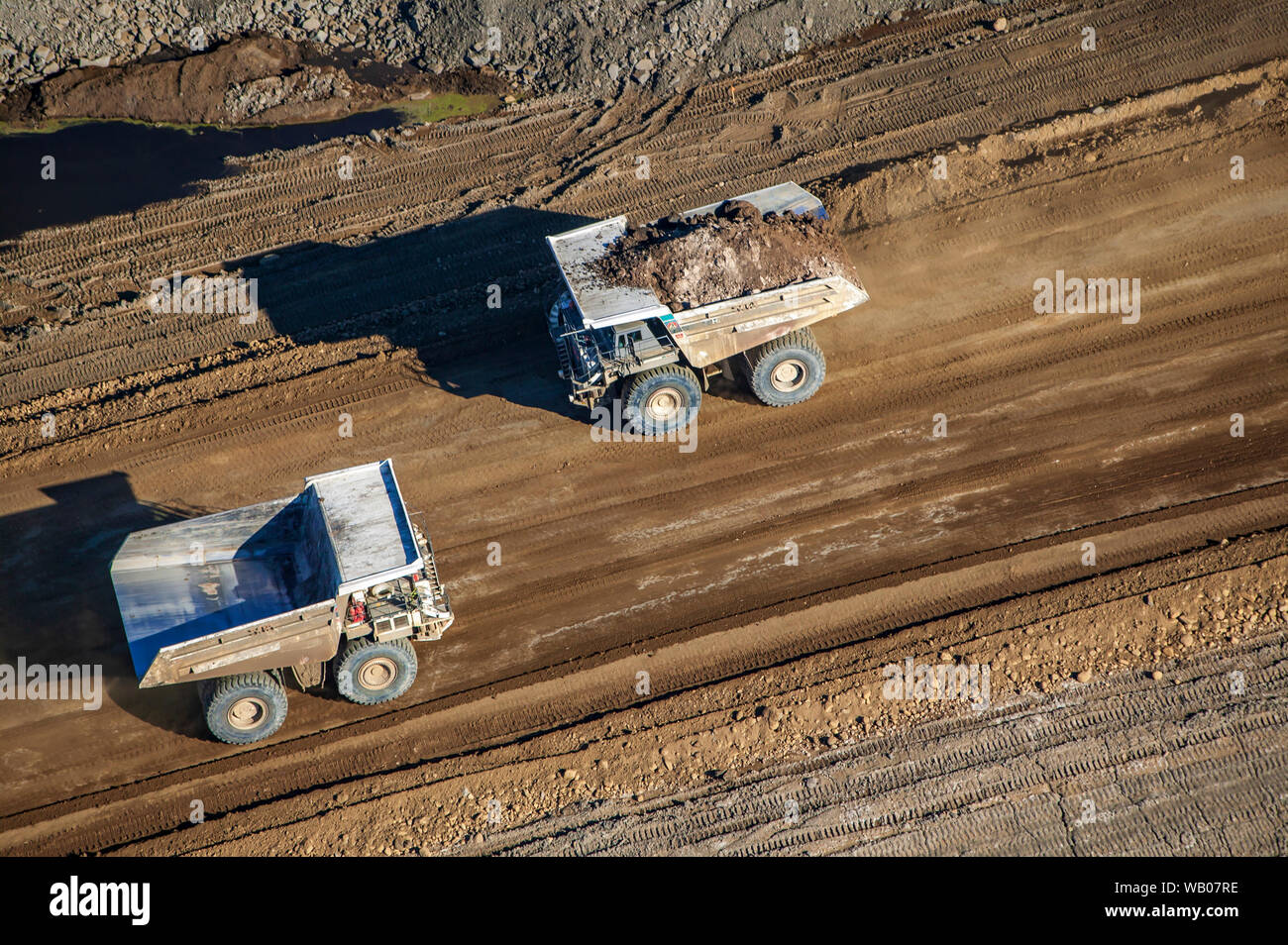 Giant trucks haul bitumen rich ore from mining operations to oil sands ...