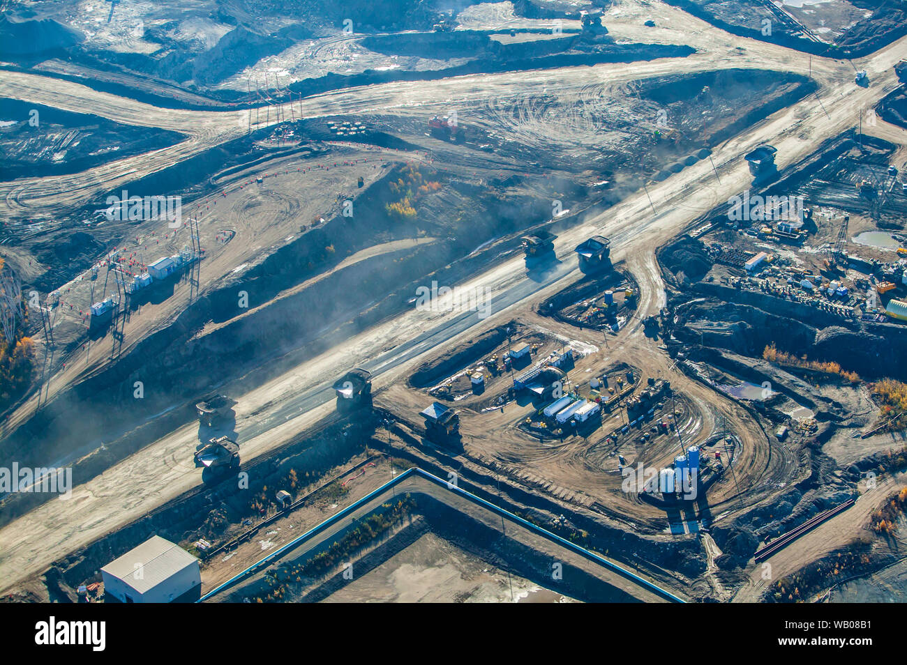 Giant trucks haul bitumen rich ore from mining operations to oil sands ...