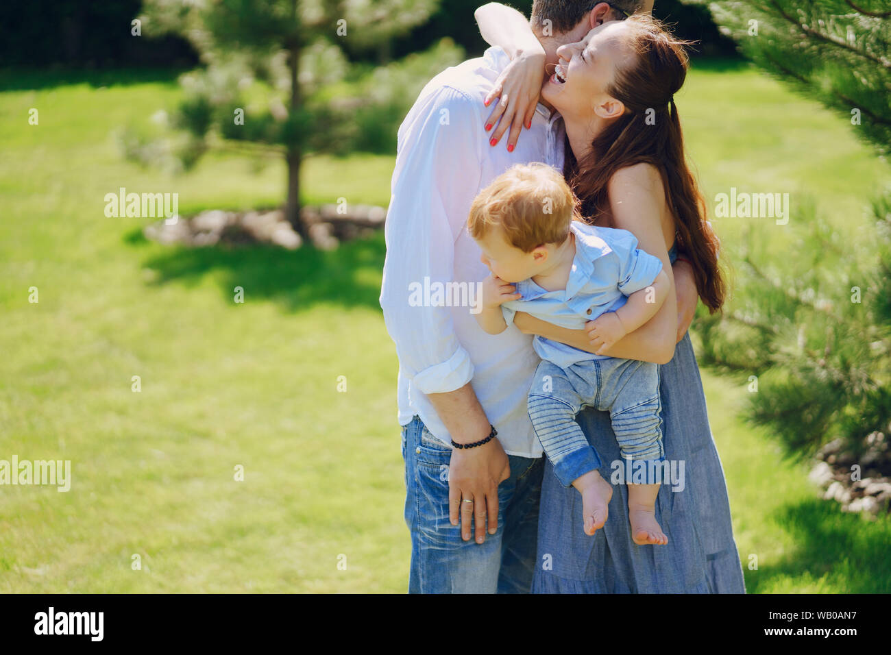 beautiful long-haired mother in a long blue dress in sunny summer ...