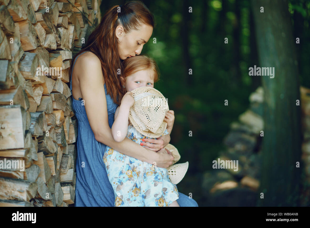 beautiful long-haired mother in a long blue dress in sunny summer ...
