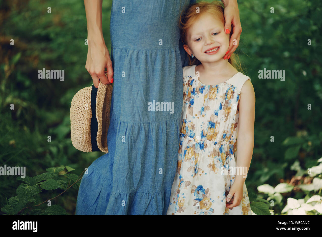beautiful long-haired mother in a long blue dress in sunny summer ...