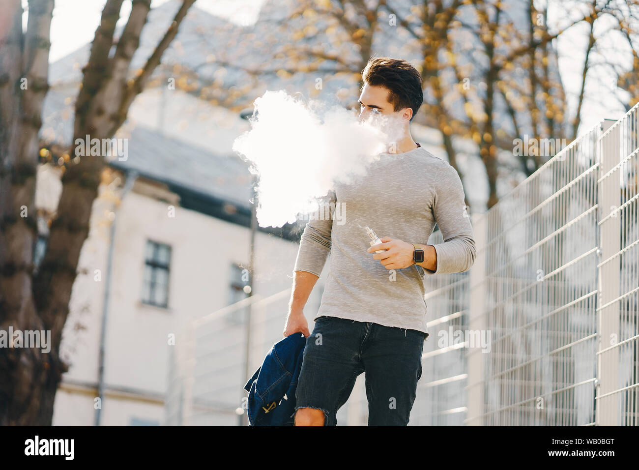 stylish man walking through the city smoking an e-cigarette Stock Photo ...