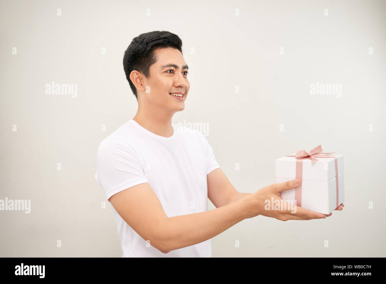 A happy handsome man presenting some gifts. Isolated on white ...