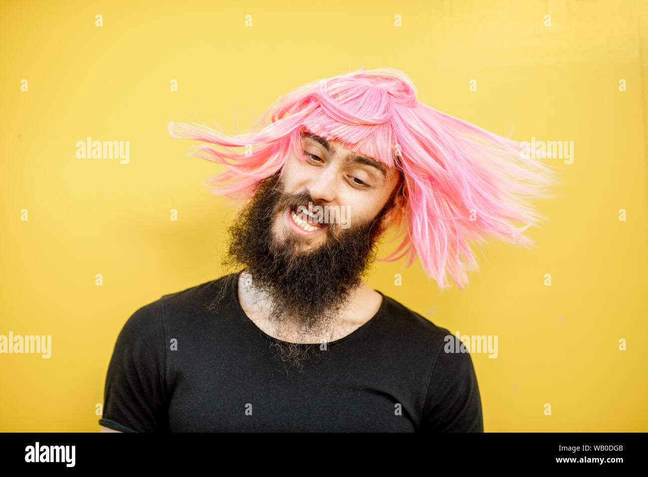 Funny portrait of a stylish playful man with beard and long color hair ...