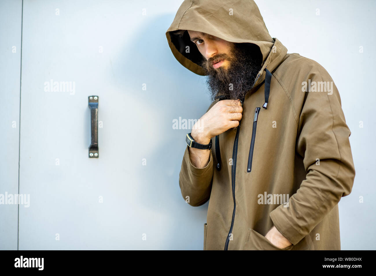 Portrait of a mysterious and weird man wearing hoodie coat on the blue ...