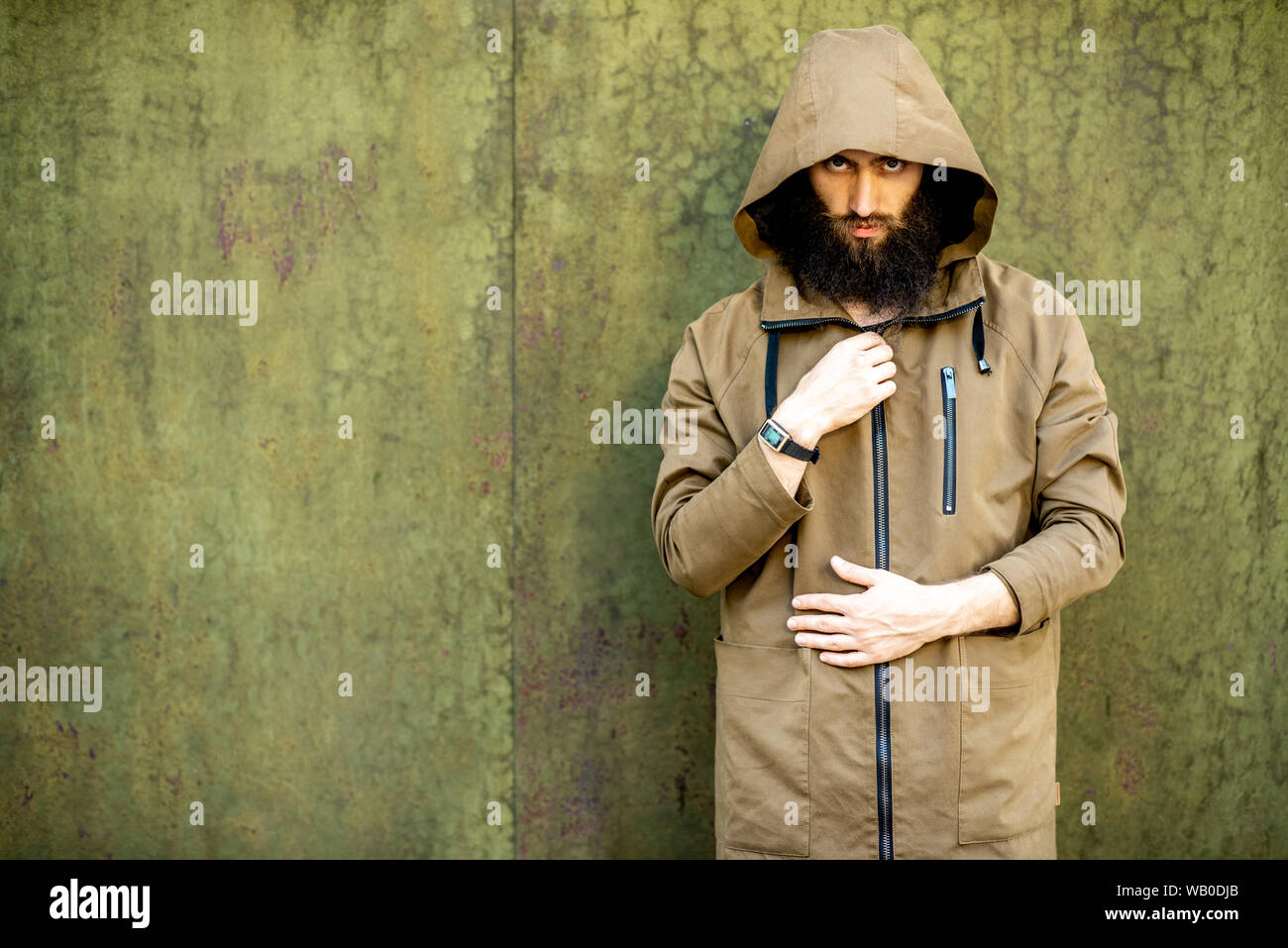 Portrait of a mysterious and weird man wearing hoodie coat on the green ...