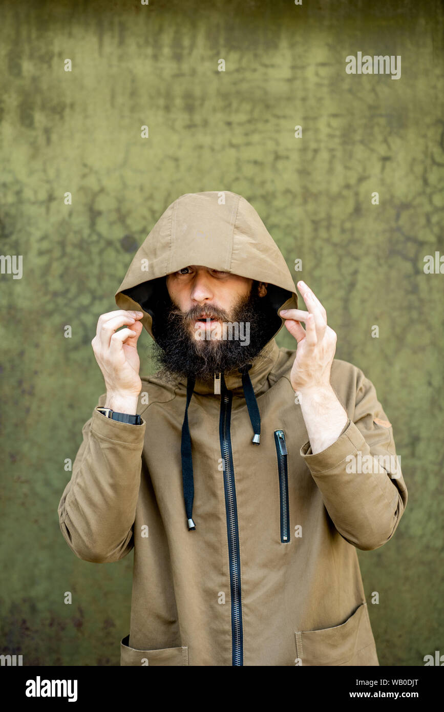 Portrait of a mysterious and weird man wearing hoodie coat on the green ...