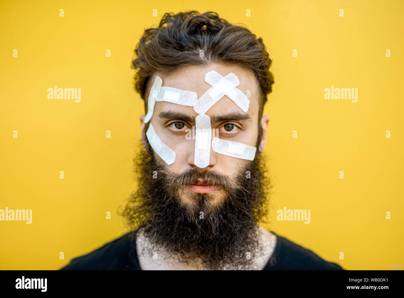 Close-up portrait of an injured man with medical patches on his face on ...